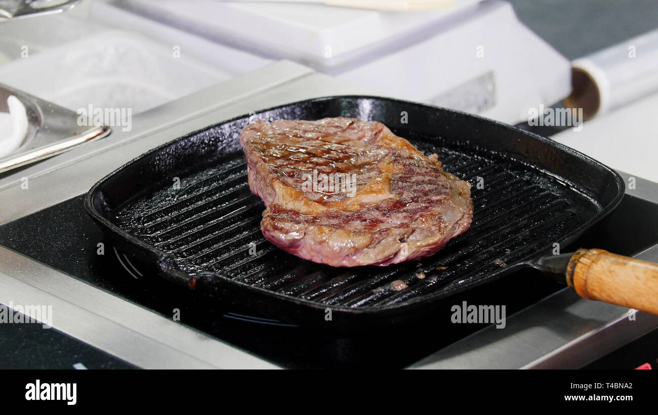 A chef working in the kitchen. Frying a piece of steak in the pan Stock ...