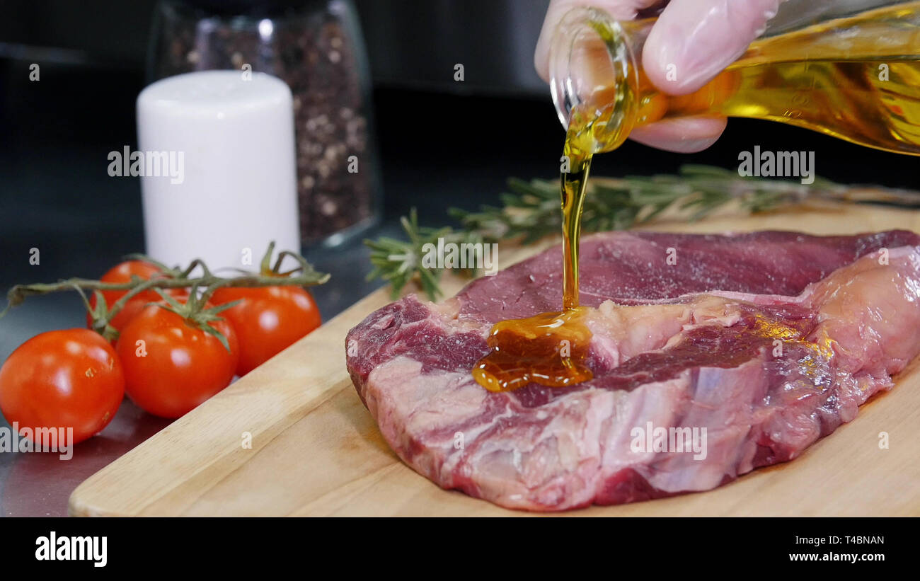 Working in the kitchen. Chef preparing the meat. Pouring an oil Stock ...