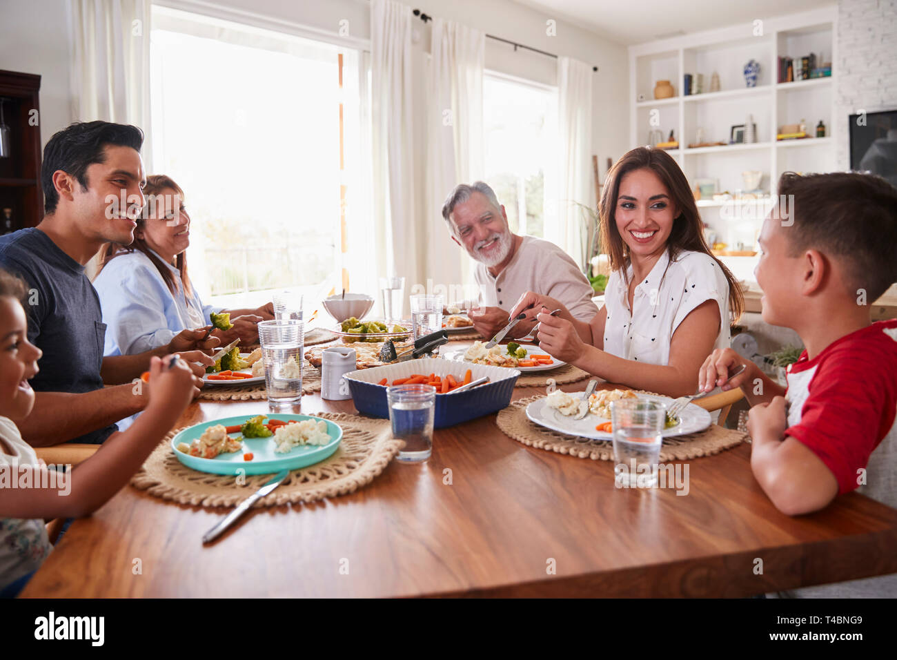 Three generation Hispanic family sitting at the table eating dinner ...