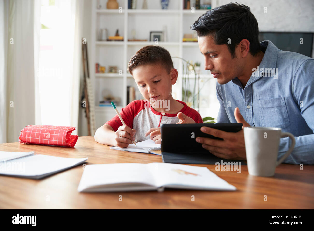 Hispanic pre-teen boy sitting at dining table working with his home ...