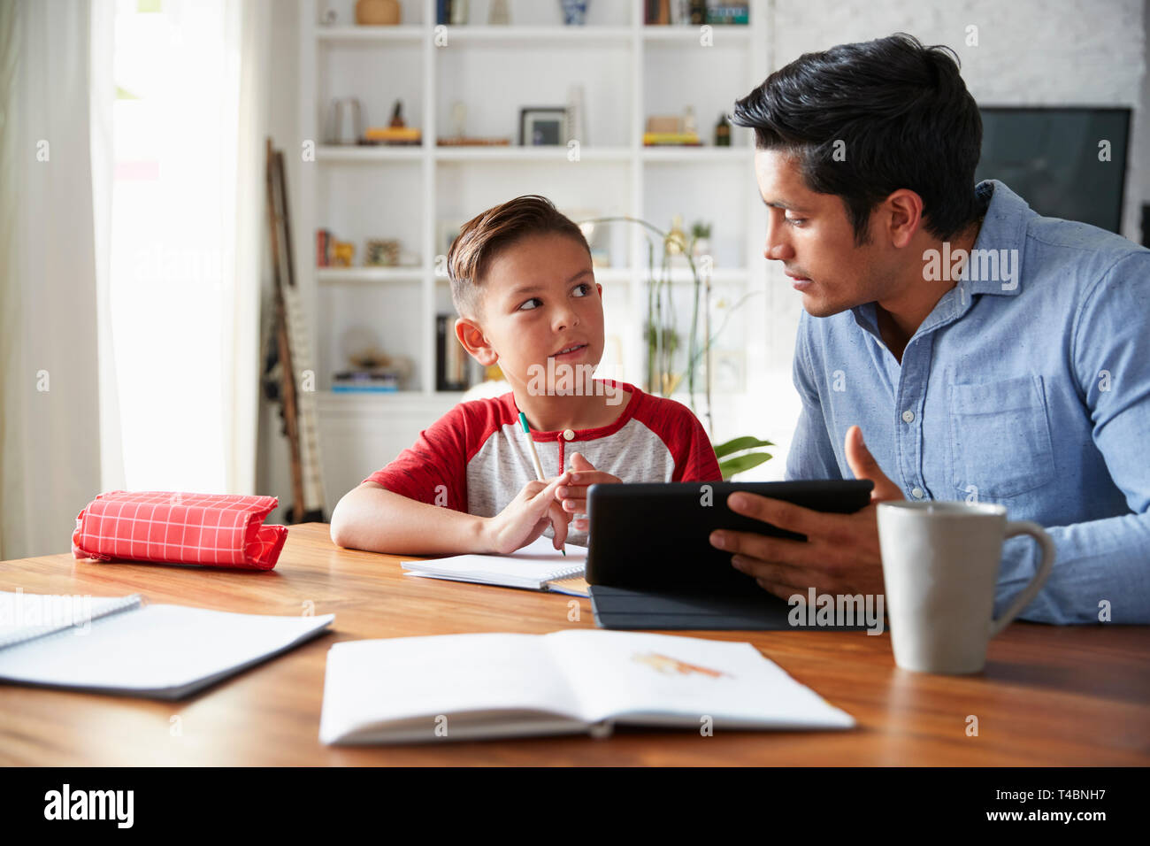 Hispanic pre-teen boy sitting at dining room table working with his ...