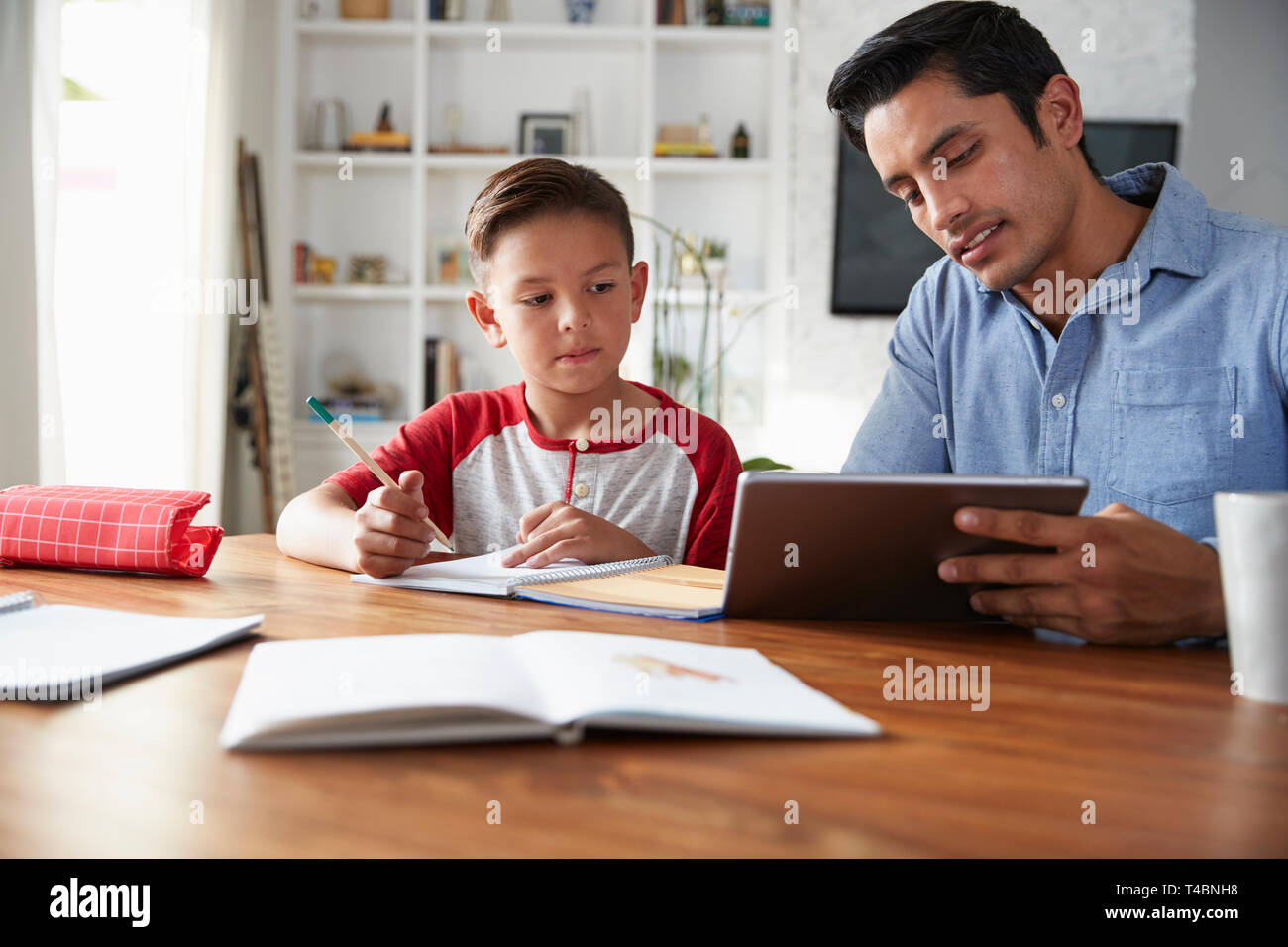 Hispanic pre-teen boy sitting at table working with his home school ...