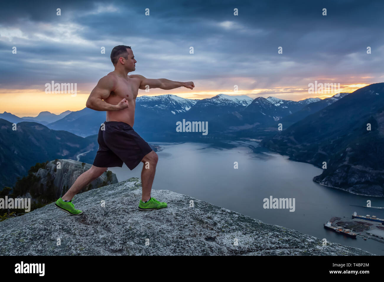 Fit and Muscular Young Man is practicing martial arts on top of the ...