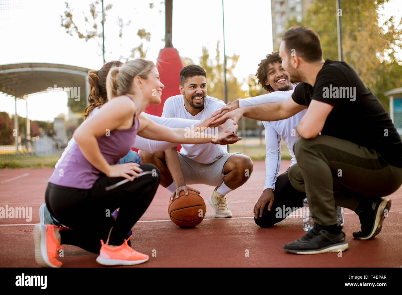 Multiethnic group of young basketball players resting on court together ...