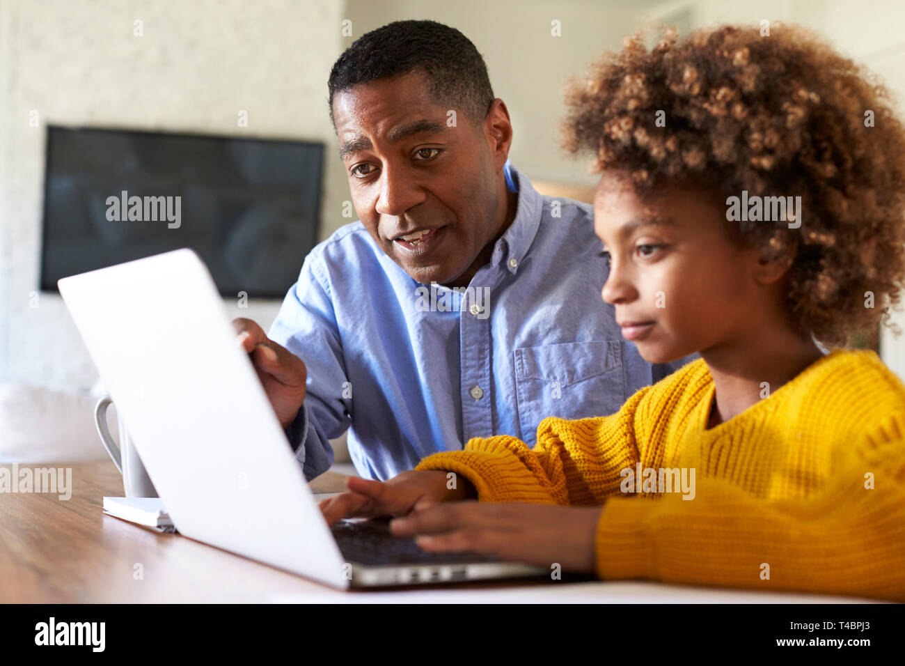 Pre teen girl black girl using a laptop computer sitting at table in ...