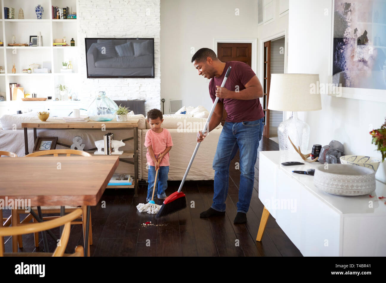 Grandfather and his three year old grandson mopping and sweeping the ...