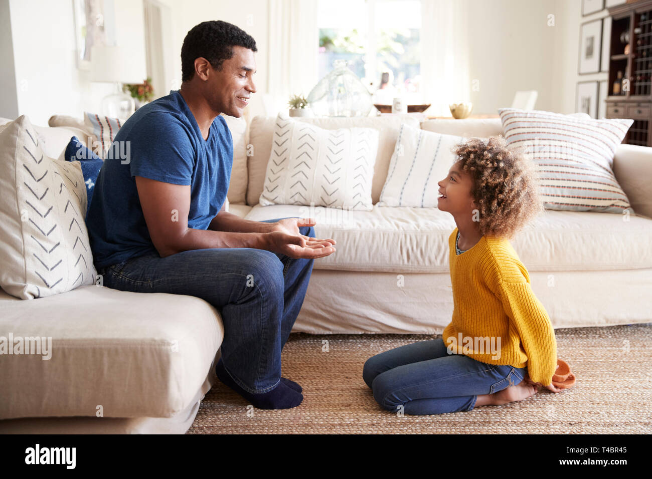 Pre-teen girl kneeling in front of her dad to give him a present she ...