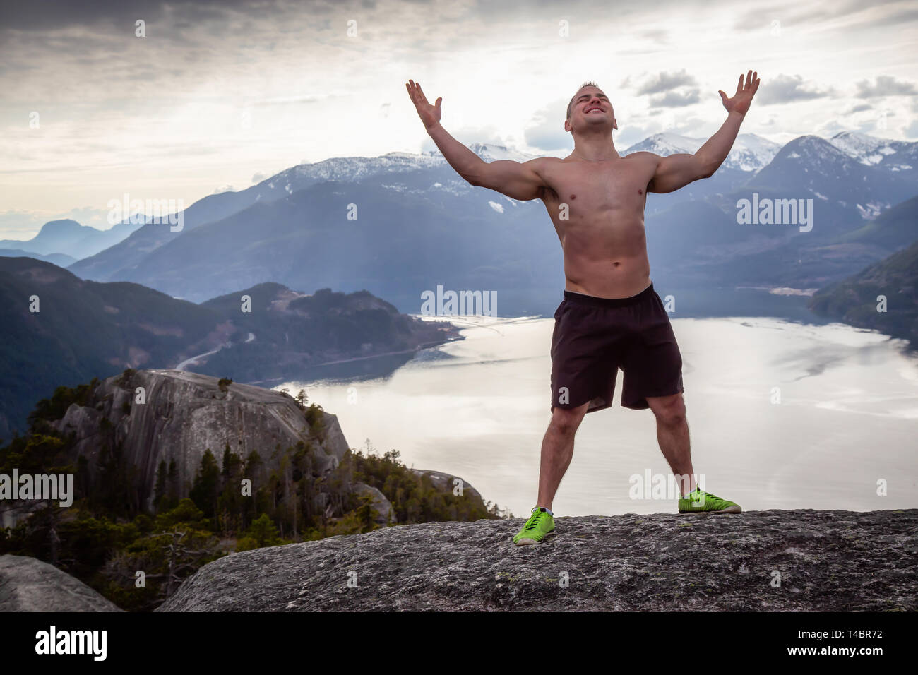 Fit and Muscular Young Man is on top of the Mountain during a cloudy ...