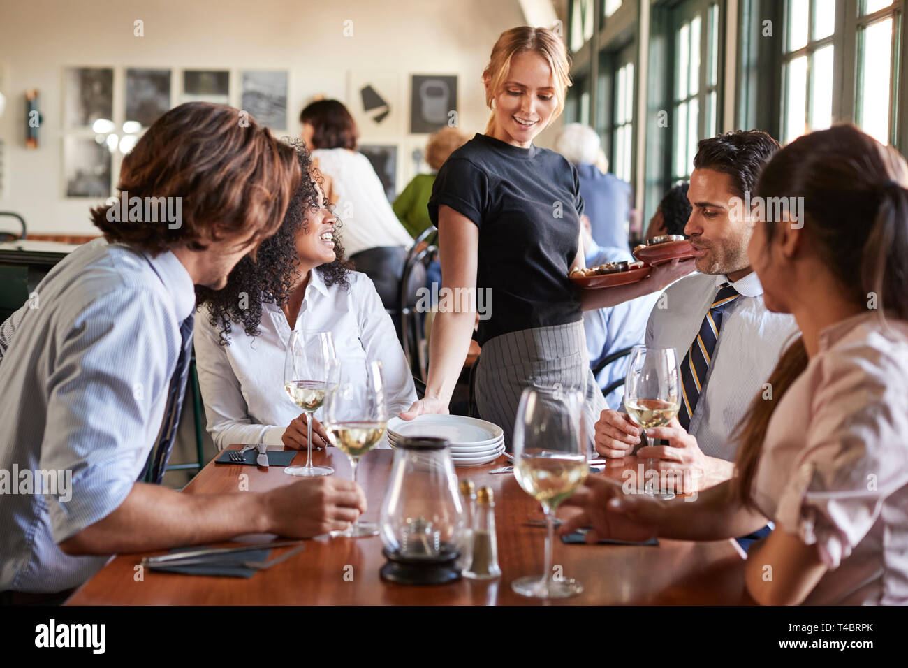 Waitress Serving Meal To Business Colleagues Sitting Around Restaurant ...