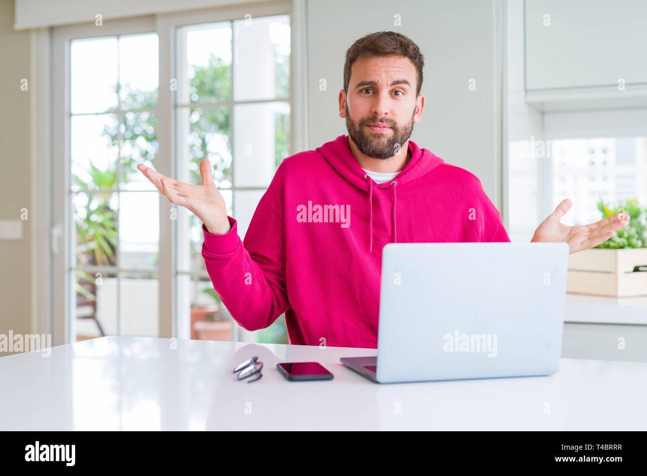 Handsome man working using computer laptop clueless and confused ...