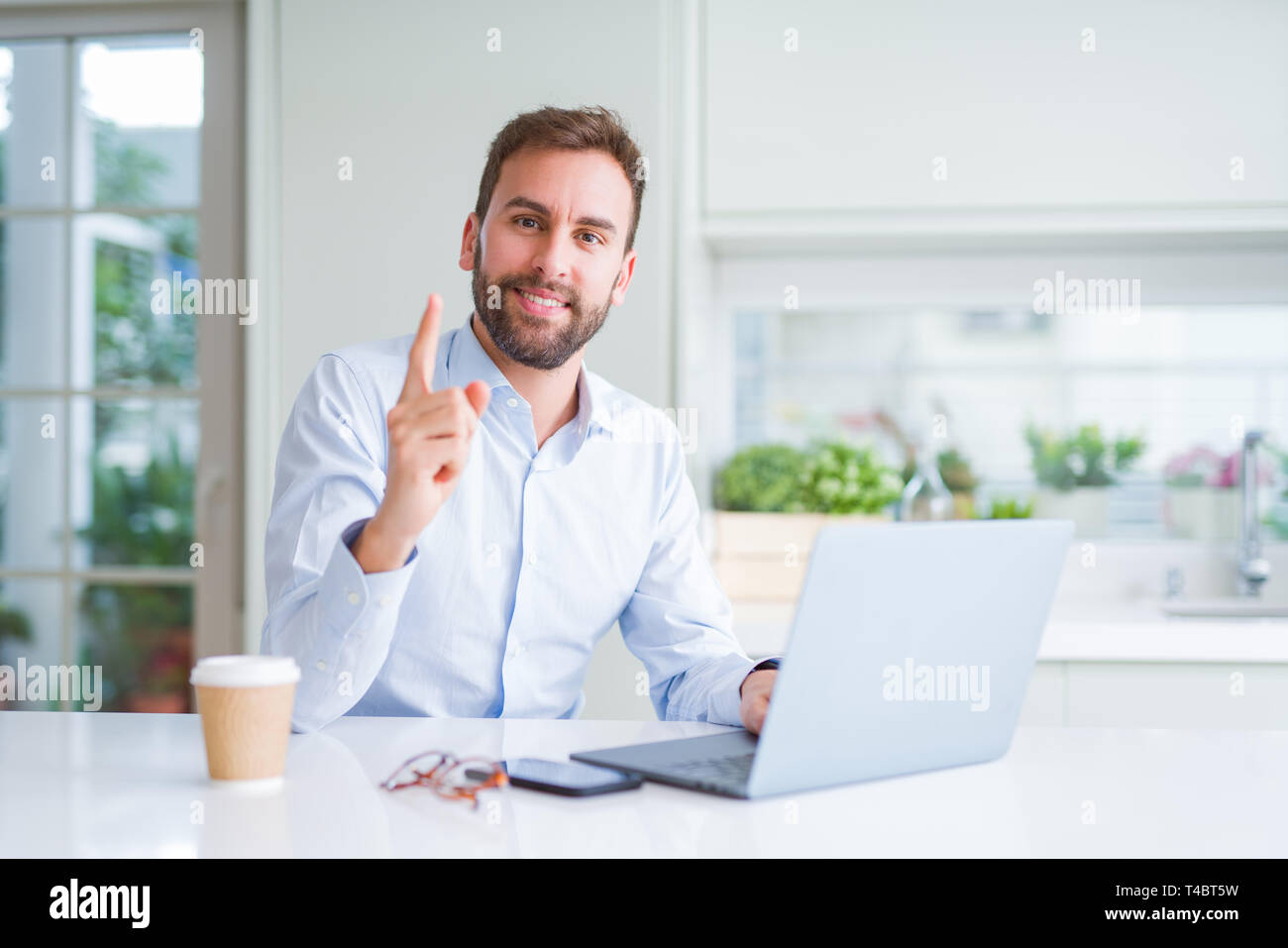 Handsome man working using computer laptop and drinking a cup of coffee ...