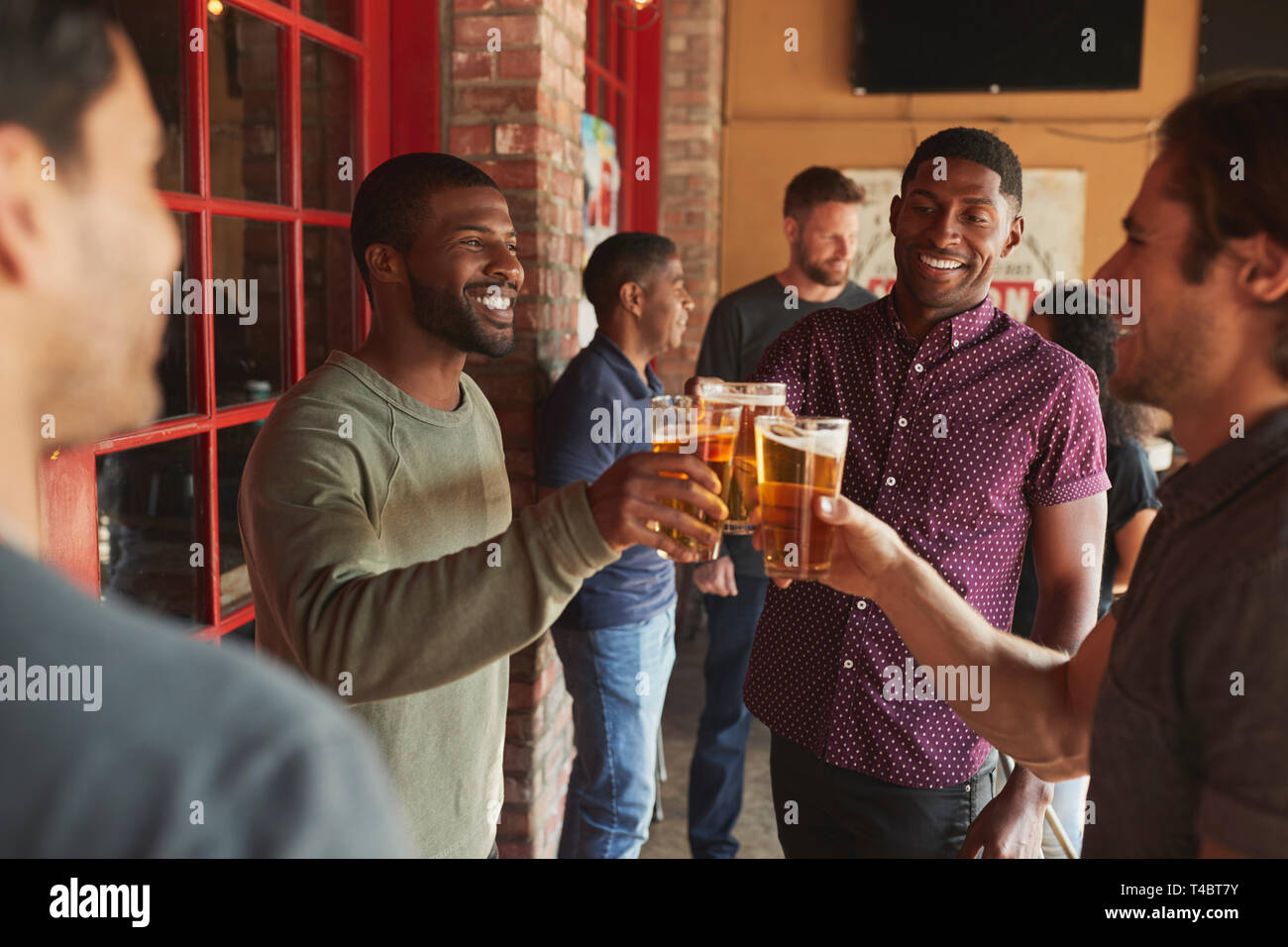 Group Of Male Friends Meeting In Sports Bar Making Toast Together Stock ...