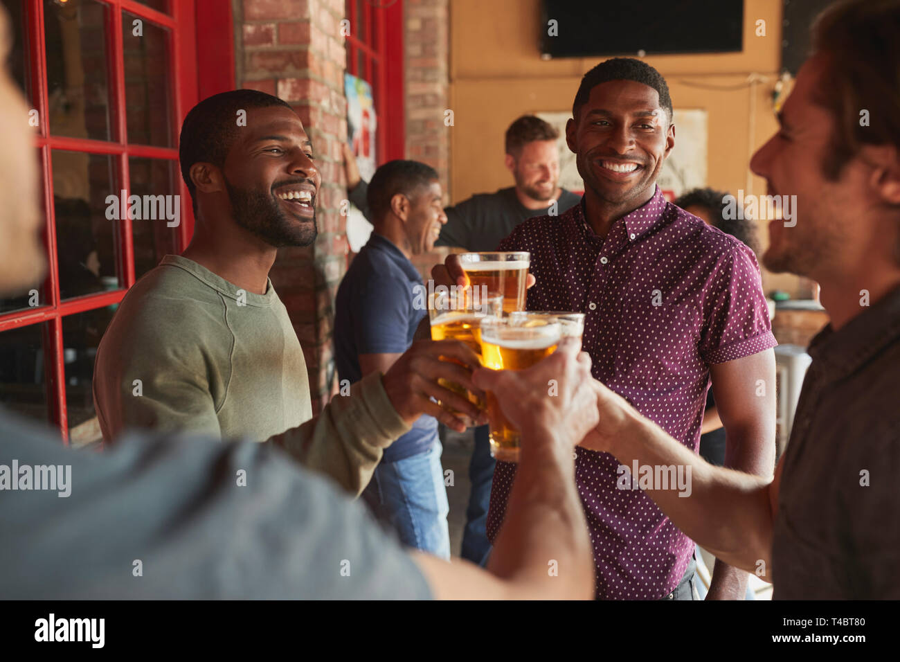 Group Of Male Friends Meeting In Sports Bar Making Toast Together Stock ...
