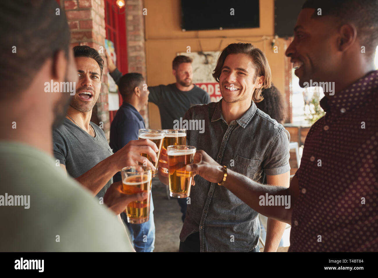 Group Of Male Friends Meeting In Sports Bar Making Toast Together Stock ...