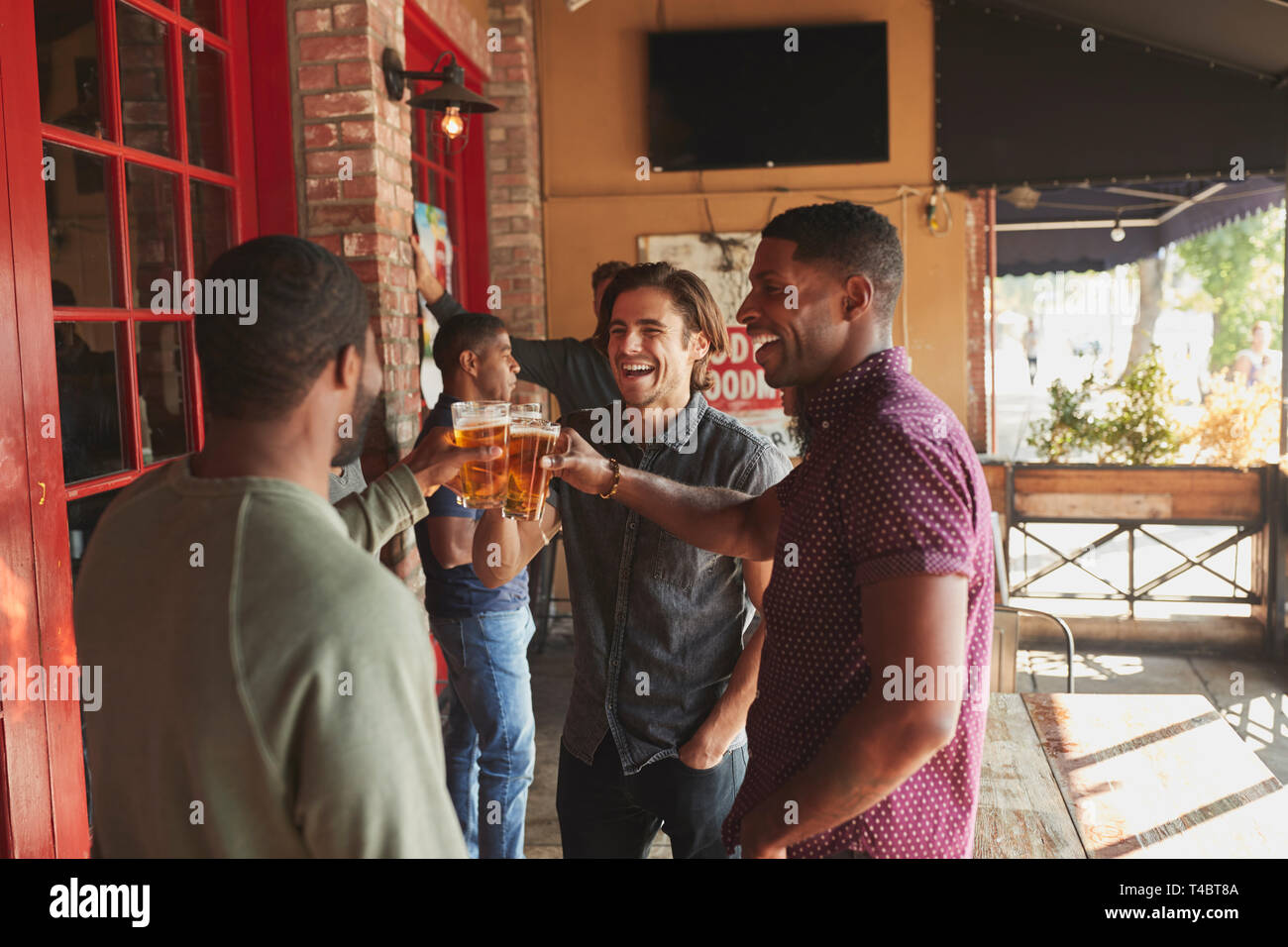 Group Of Male Friends Meeting In Sports Bar Making Toast Together Stock ...