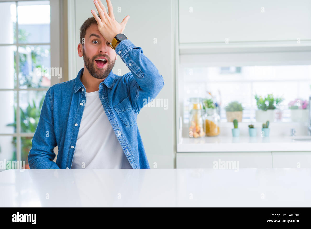 Handsome man at home surprised with hand on head for mistake, remember ...
