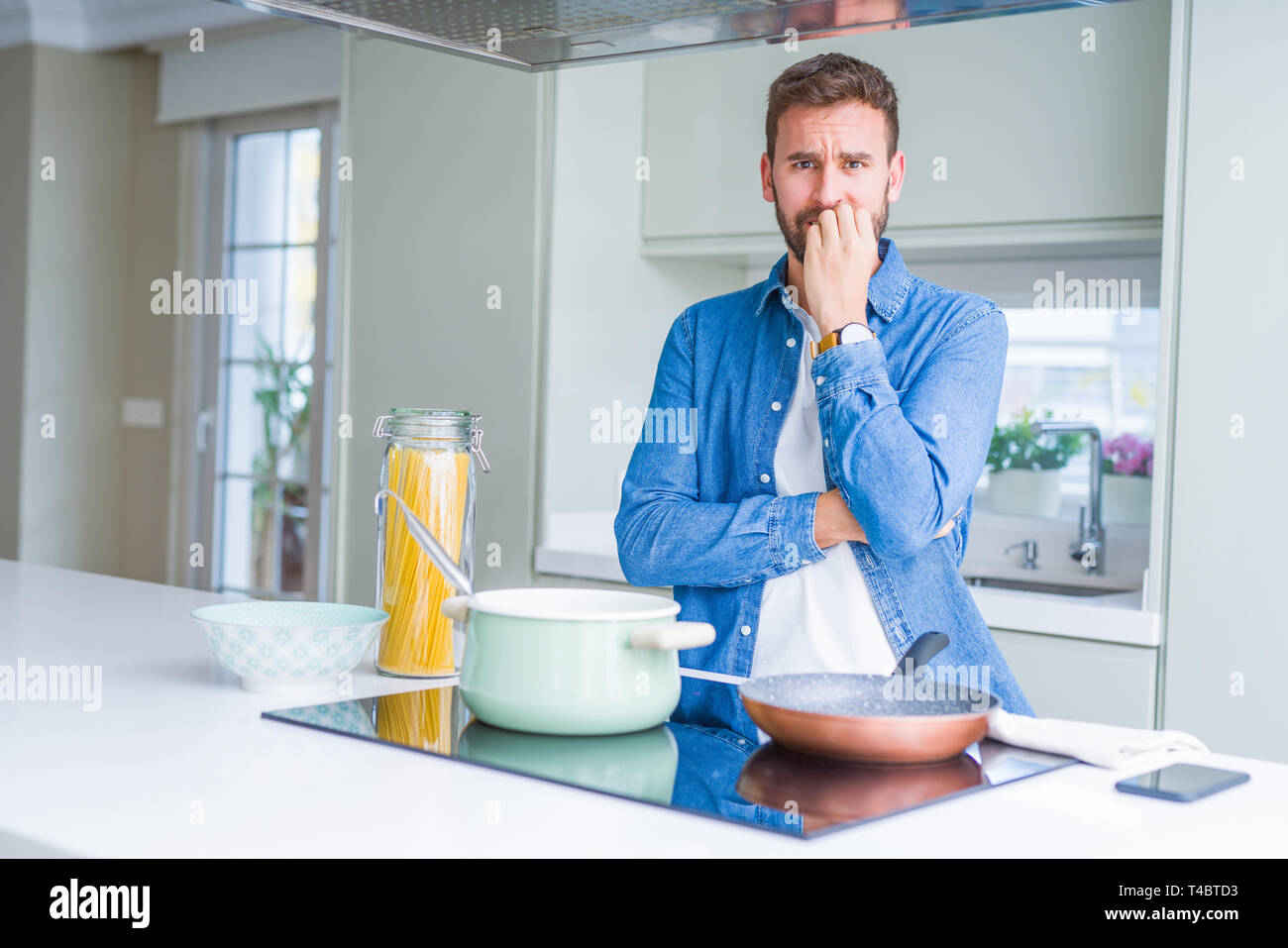Handsome man cooking italian spaghetti pasta at the kitchen looking ...