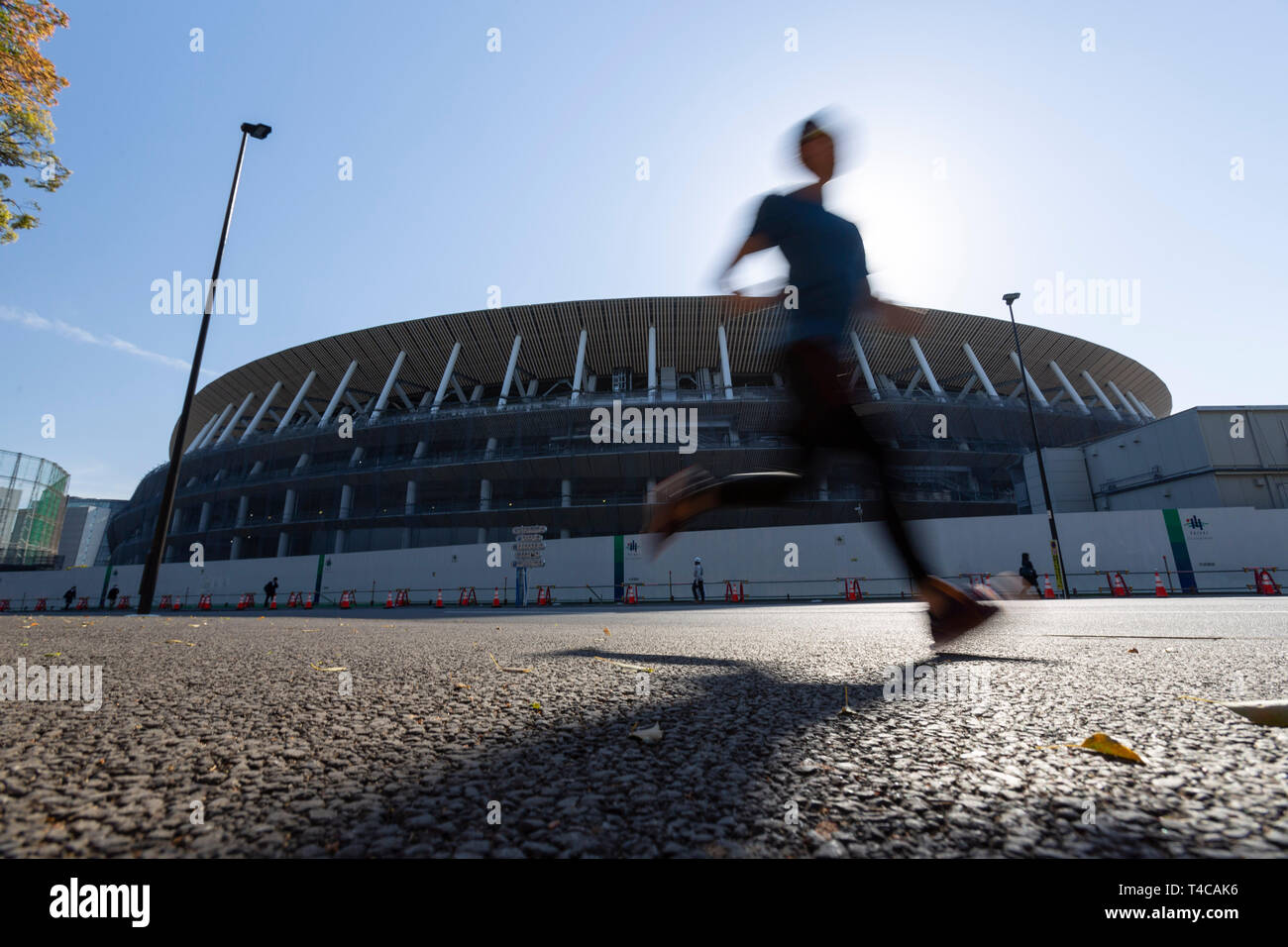 Tokyo, Japan. 16th Apr, 2019. A man runs past the New National Stadium ...