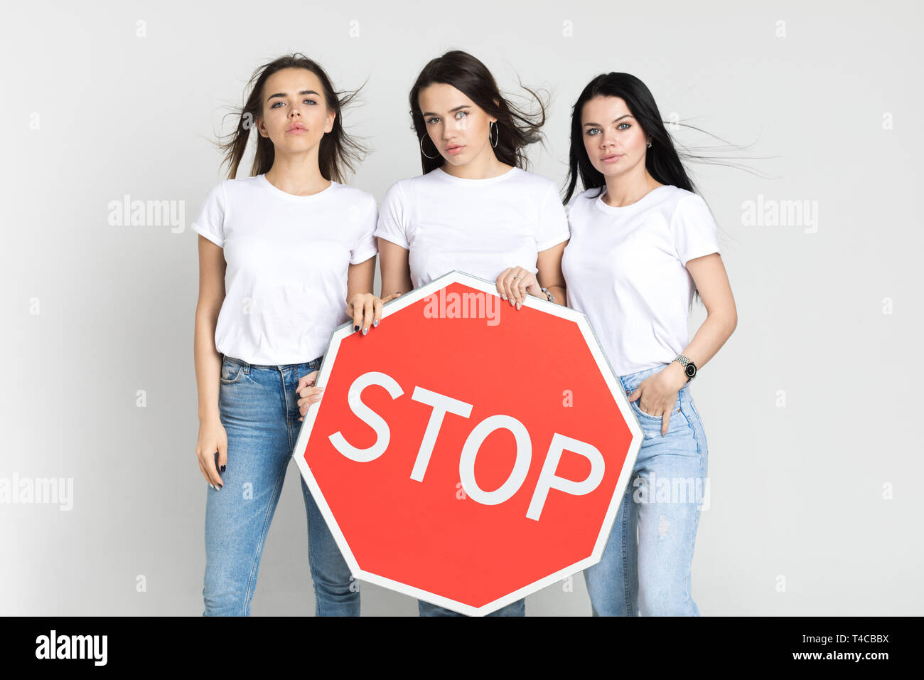 Three beautiful young women hold a big red stop sign Stock Photo - Alamy