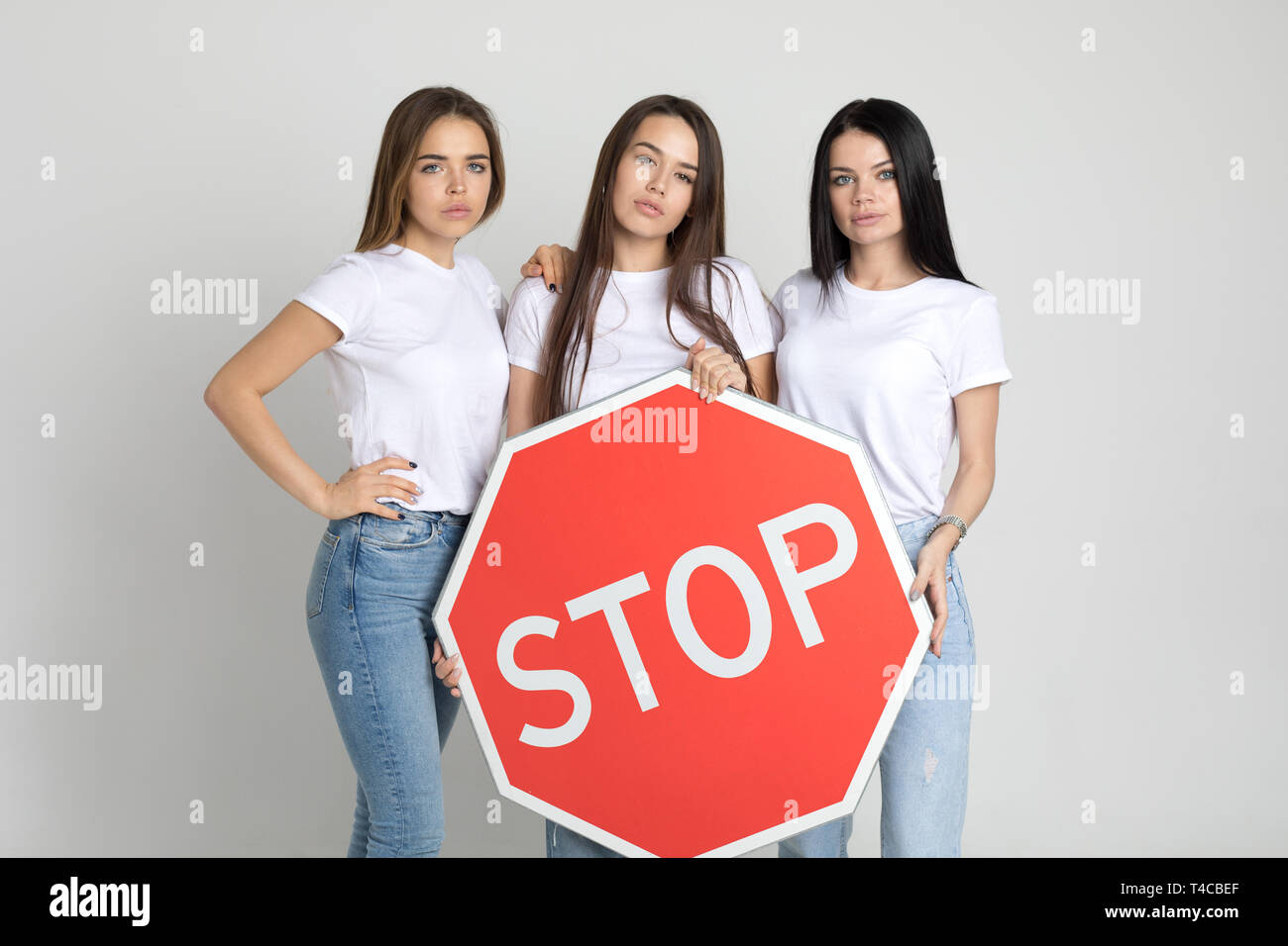 Three beautiful young women hold a big red stop sign Stock Photo - Alamy