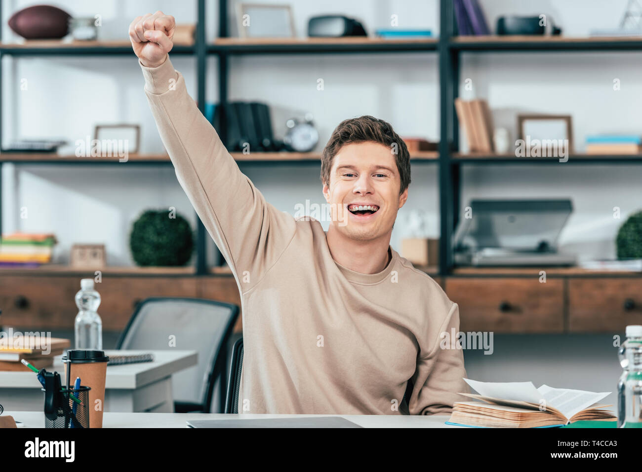 Happy laughing student sitting at table and showing yes gesture Stock ...