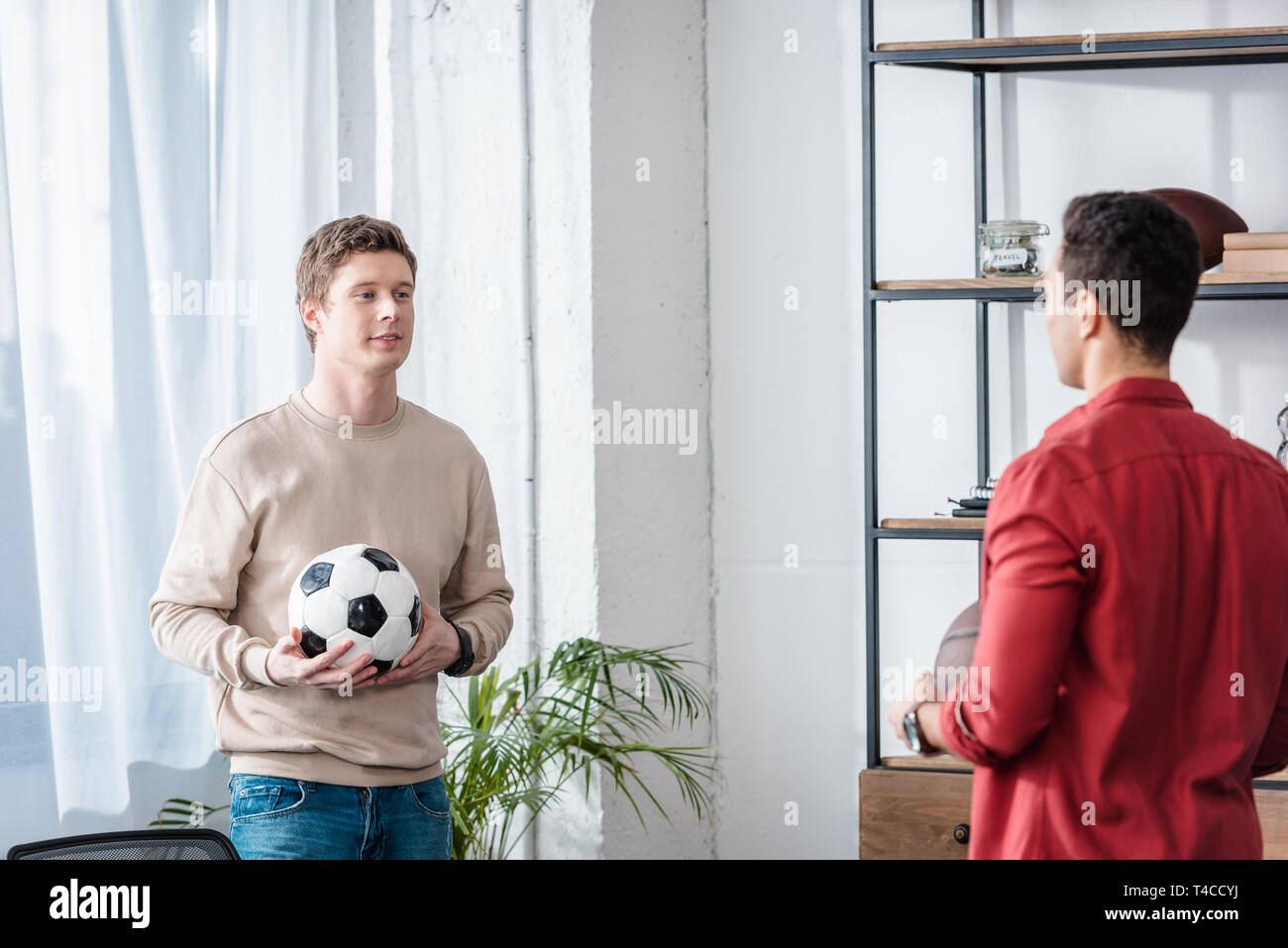 Two friends with football ball talking with smile at home Stock Photo ...