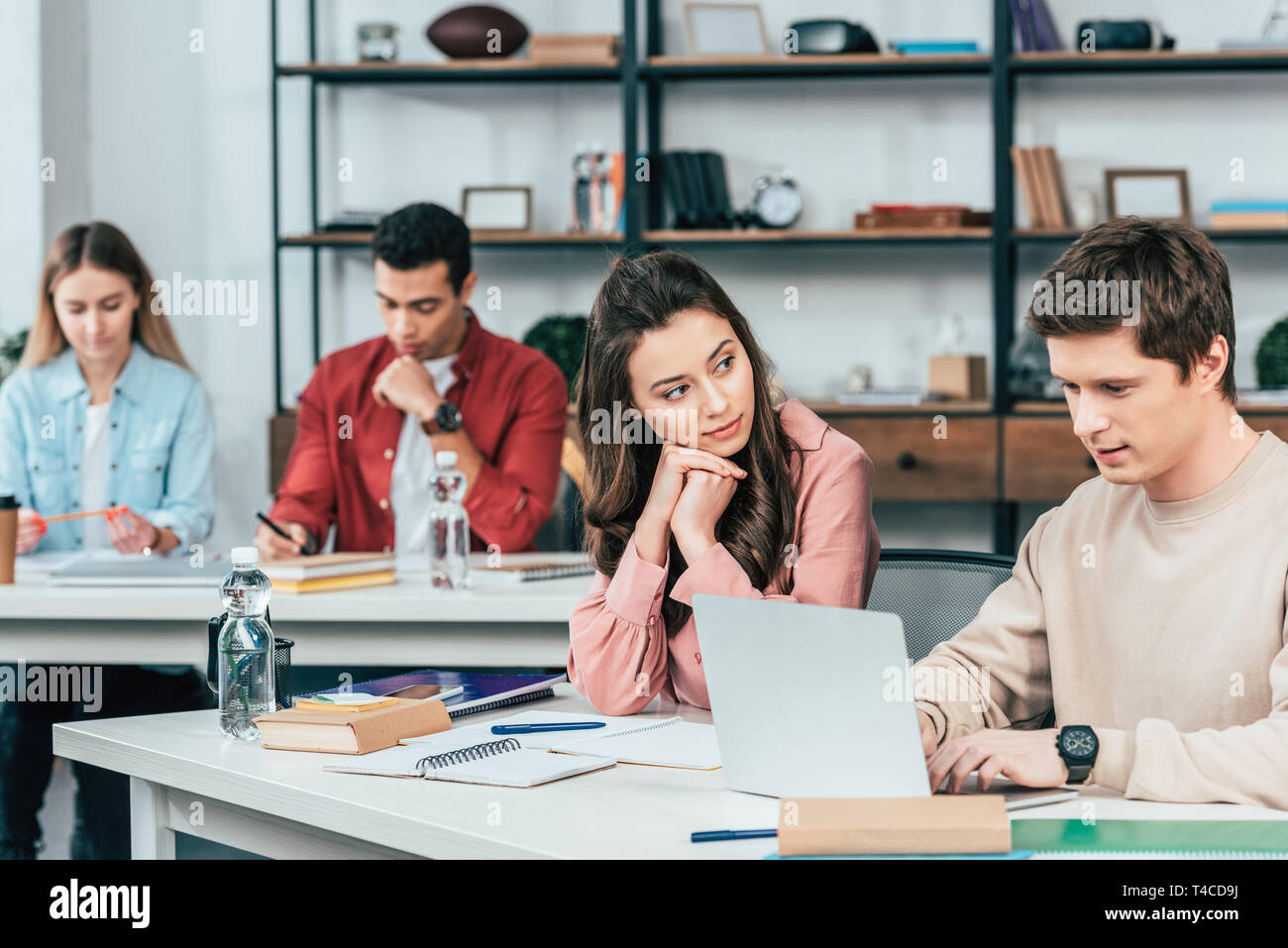 Multiethnic students sitting at desk and using laptop while studying in ...