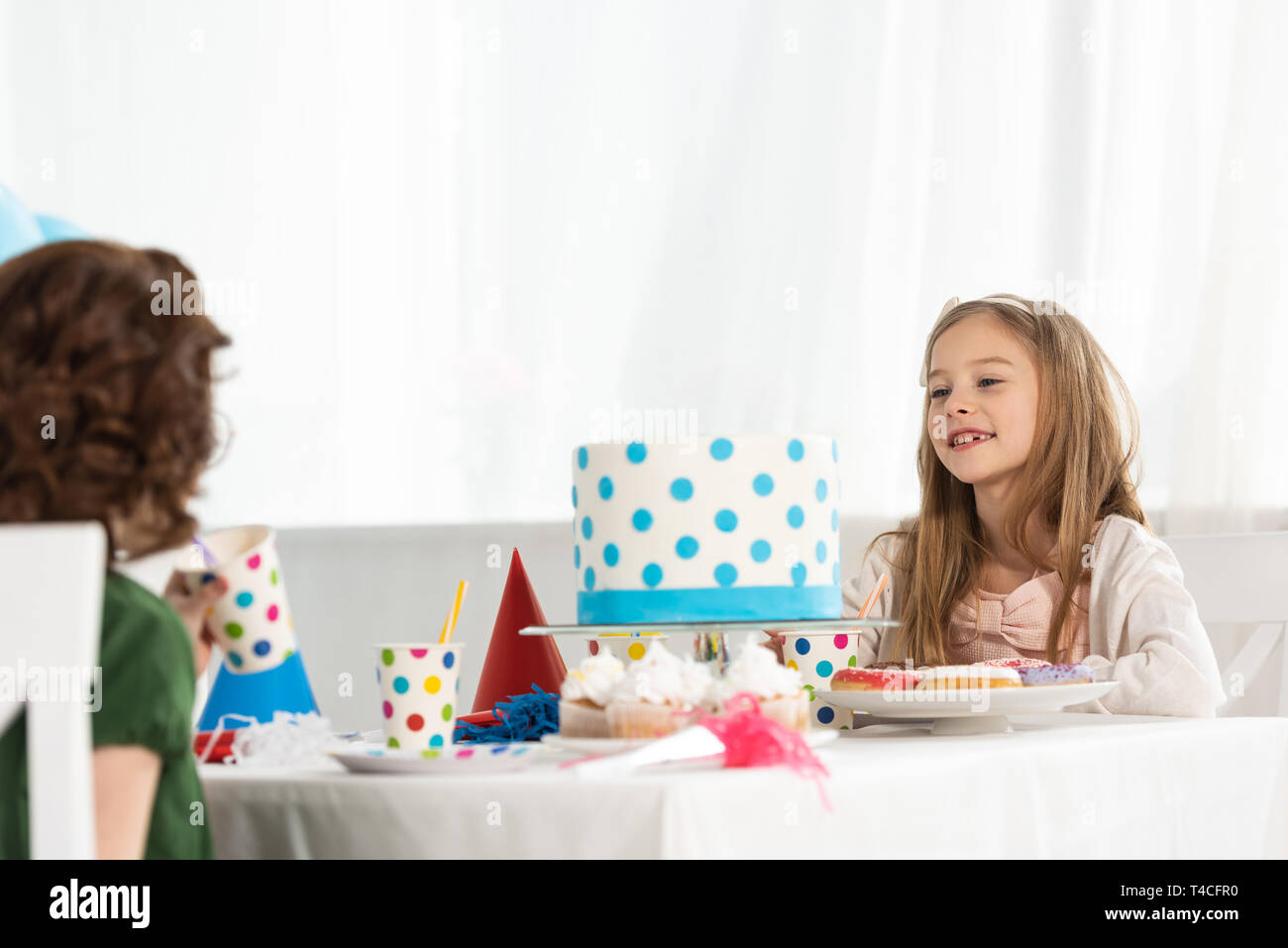 adorable kids sitting at party table with cake during birthday ...