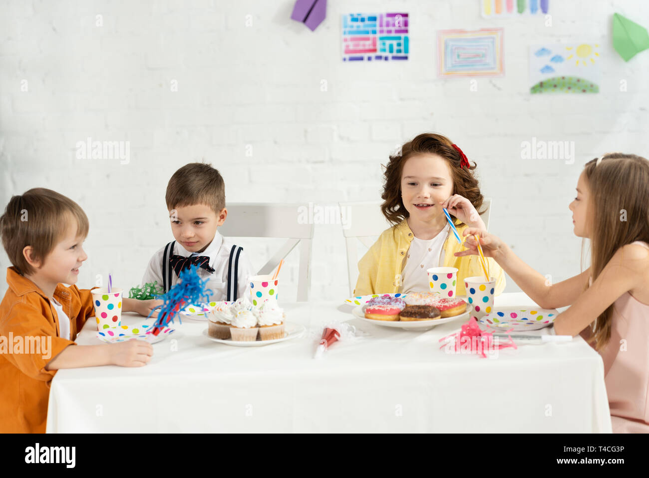kids sitting at table with cupcakes and party horns during birthday ...