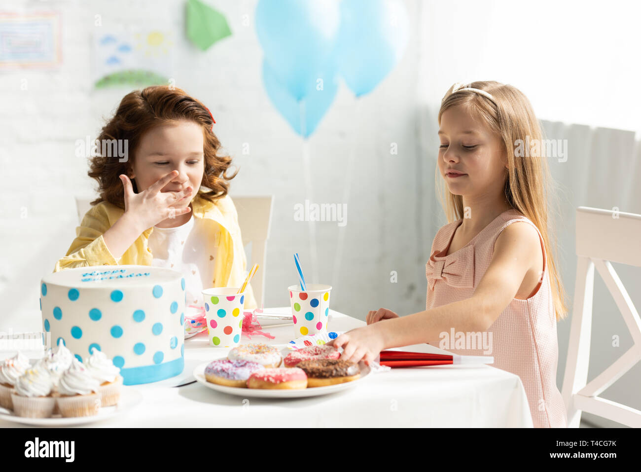 adorable kids sitting at party table with cupcakes and cake during ...