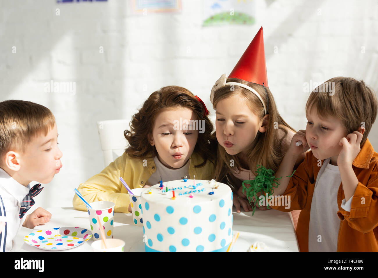 adorable kids blowing out candles on birthday cake during party at home ...