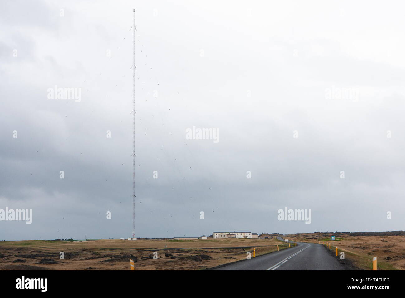 Landscape with radio tower, houses, road, horizon line, and high clouds ...