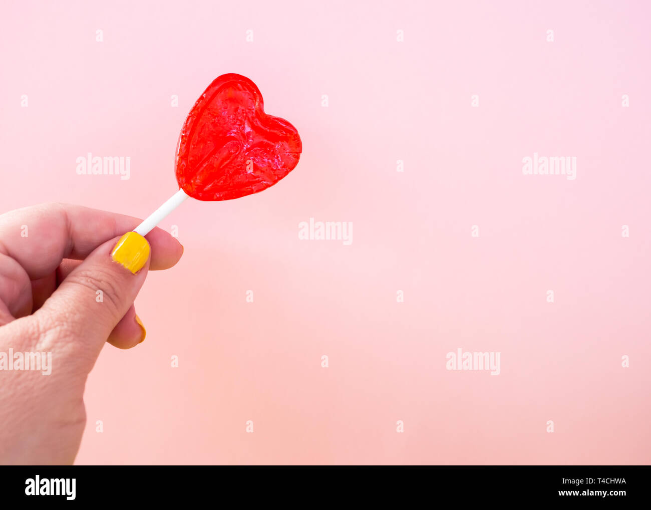A woman with yellow painted nails with a red lollipop in her hand and ...