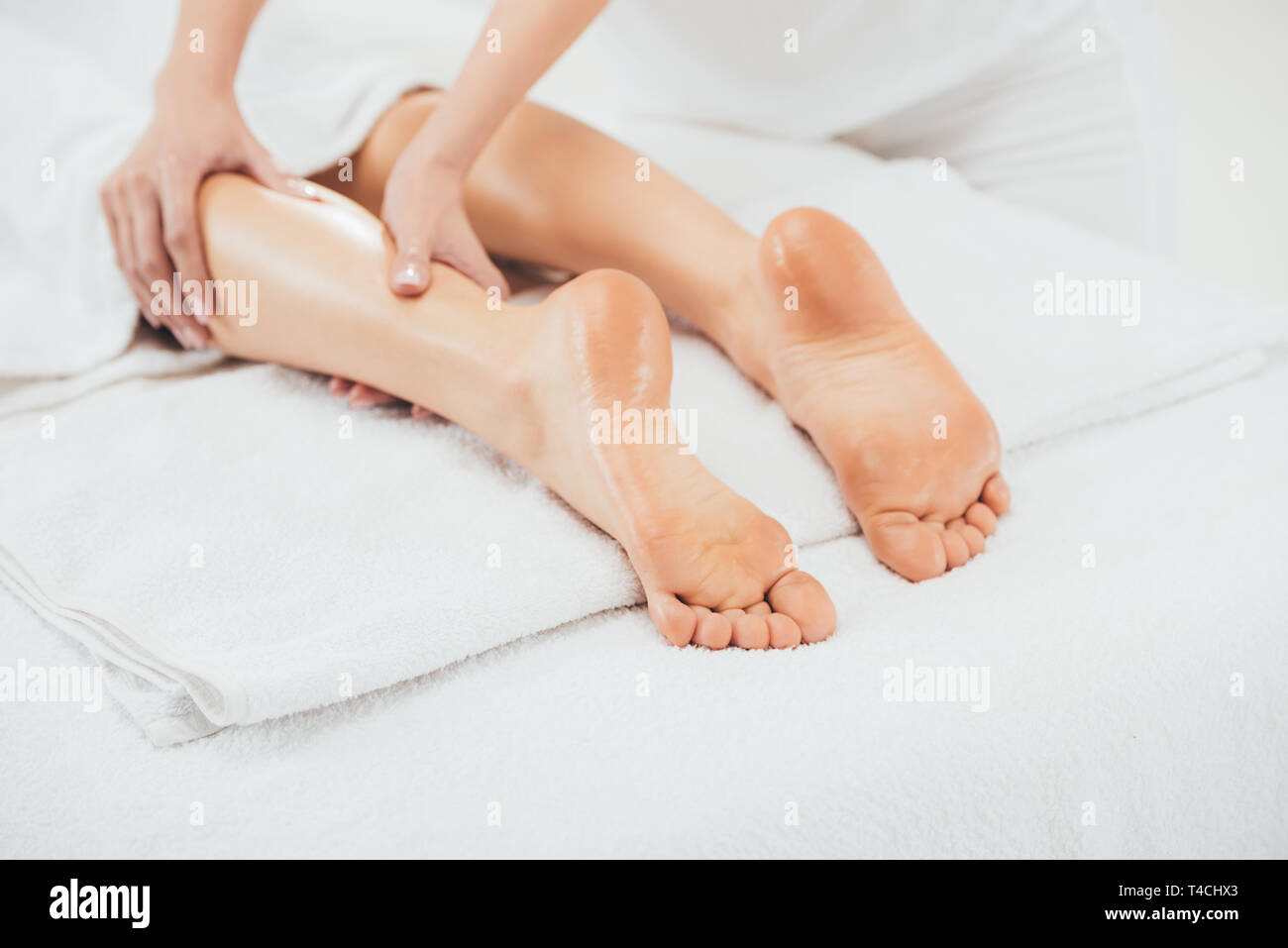 partial view of masseur doing foot massage to adult woman in spa Stock ...