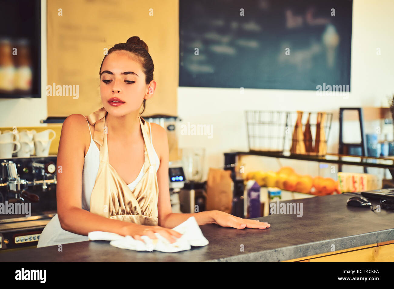 Keeping everything clean. Pretty woman stand behind cafe counter. Cute ...