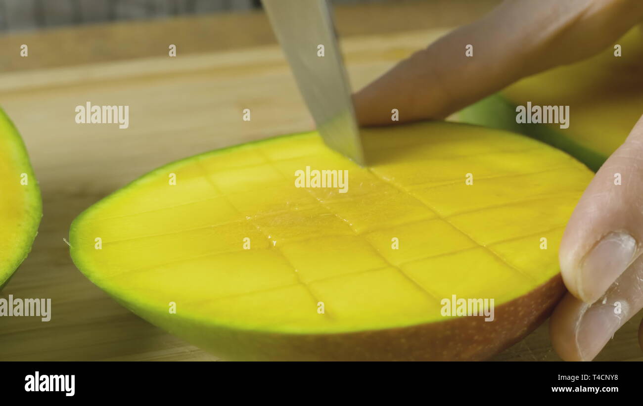 close up slo motion video of Woman hands cutting yellow mango by pieces ...