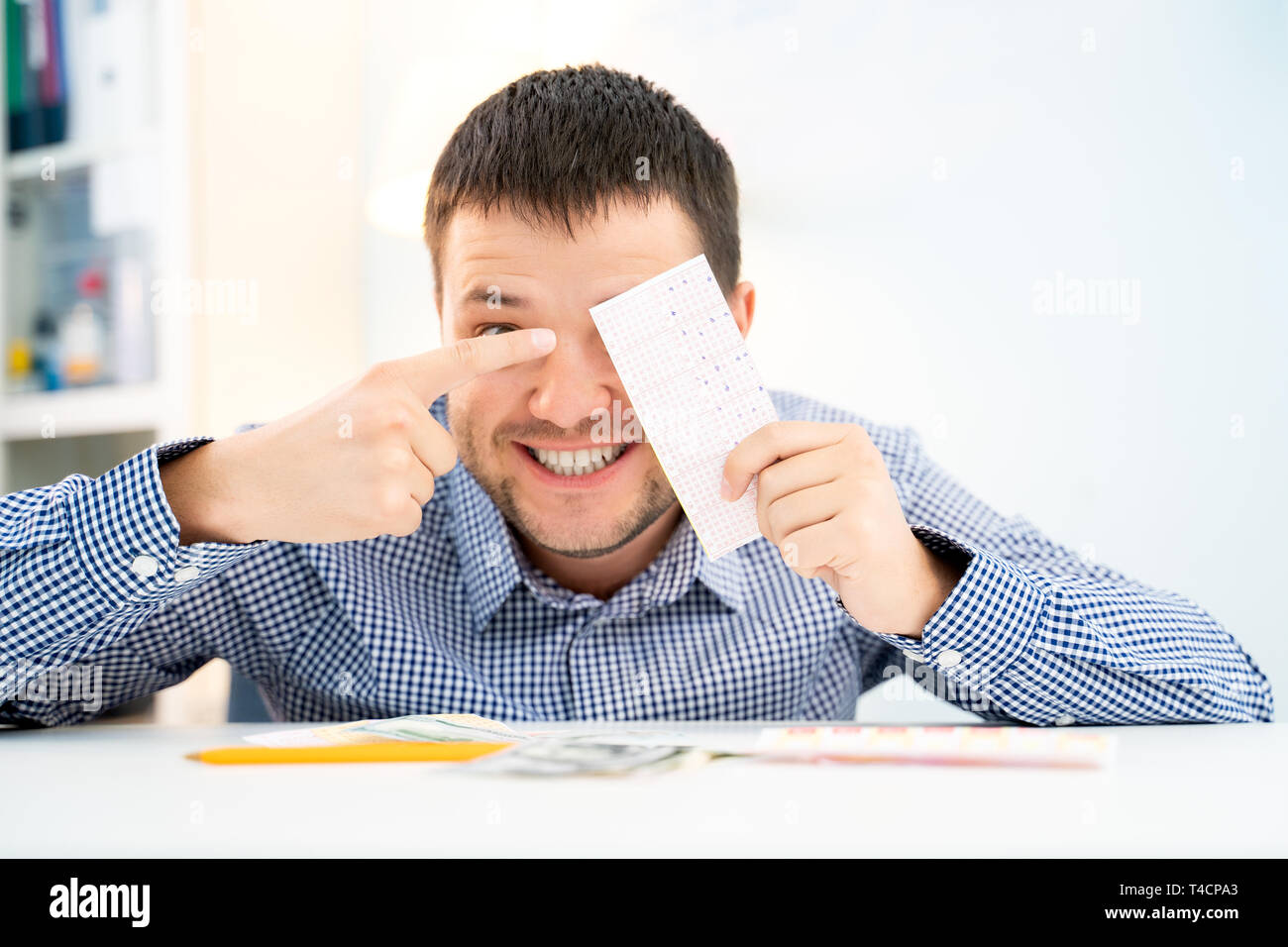 Photo of happy man with lottery ticket sitting at table Stock Photo - Alamy