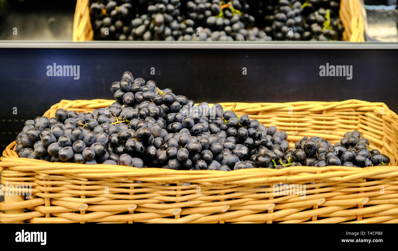 Branches of grapes in a wicker basket. Bundles of fresh ripe red grapes ...