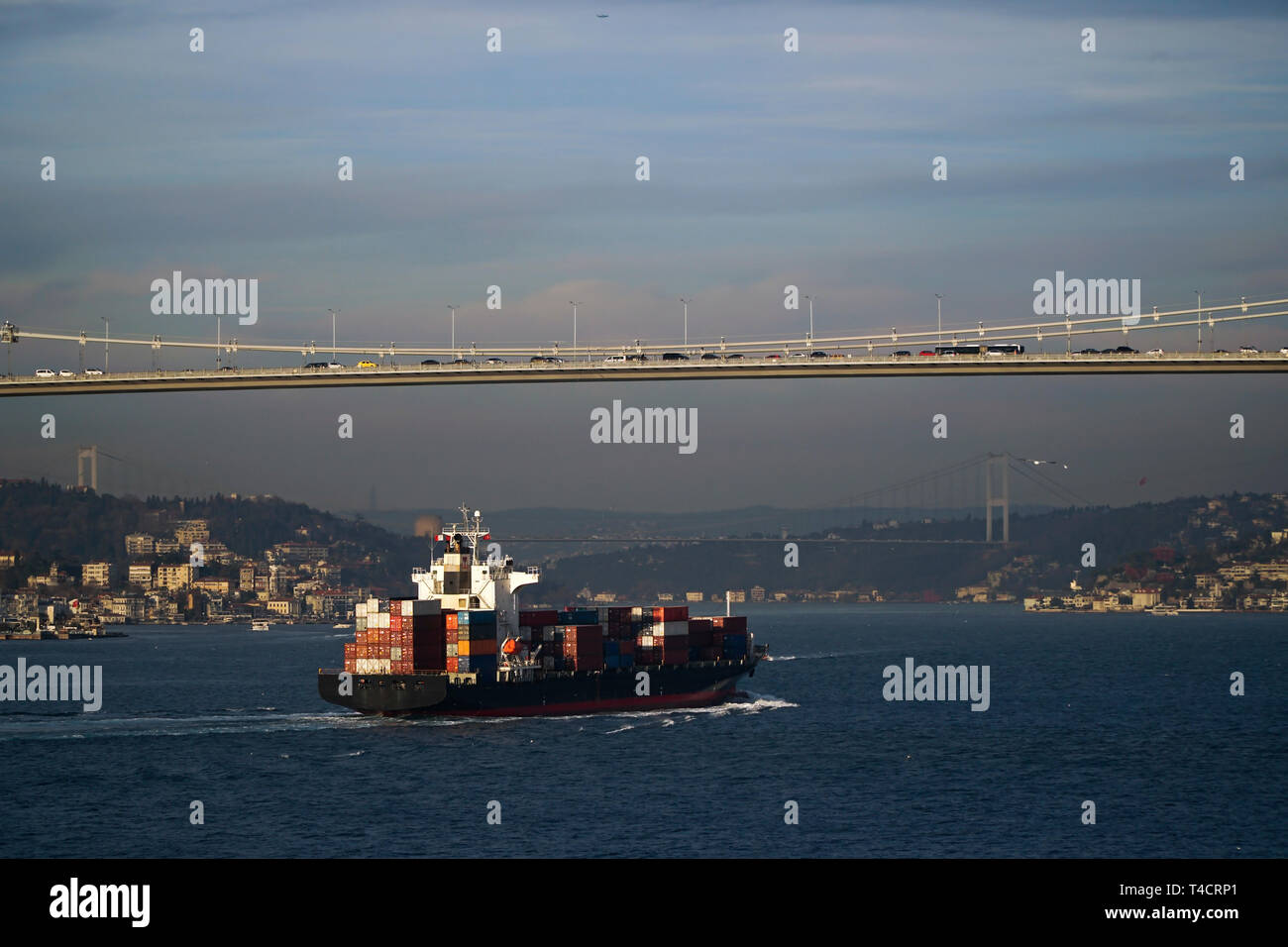 A container ship is passing under The Bosphorus Bridge in a sunny day ...