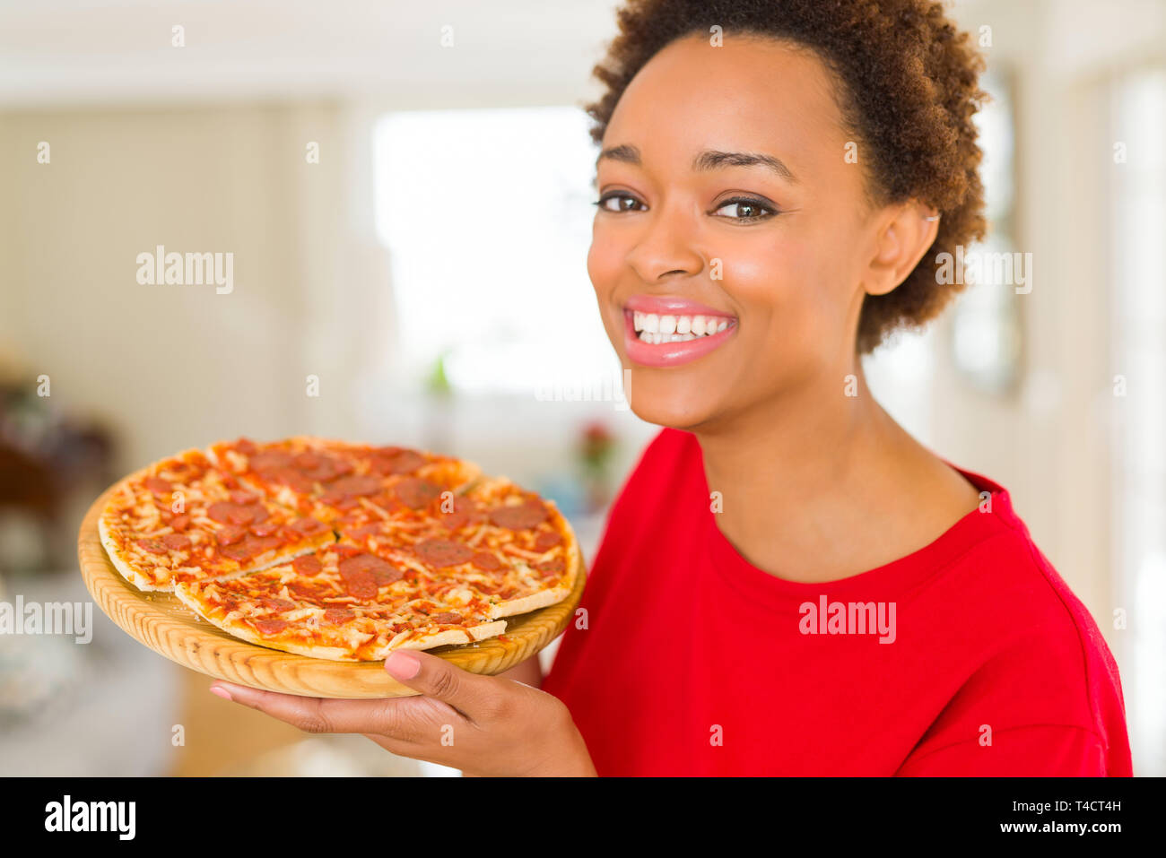 Beautiful young african american woman showing homemade tasty pizza ...