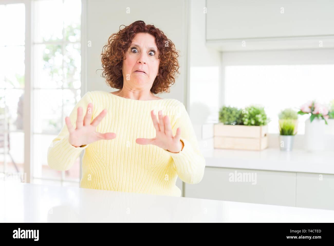Beautiful senior woman wearing yellow sweater afraid and terrified with ...