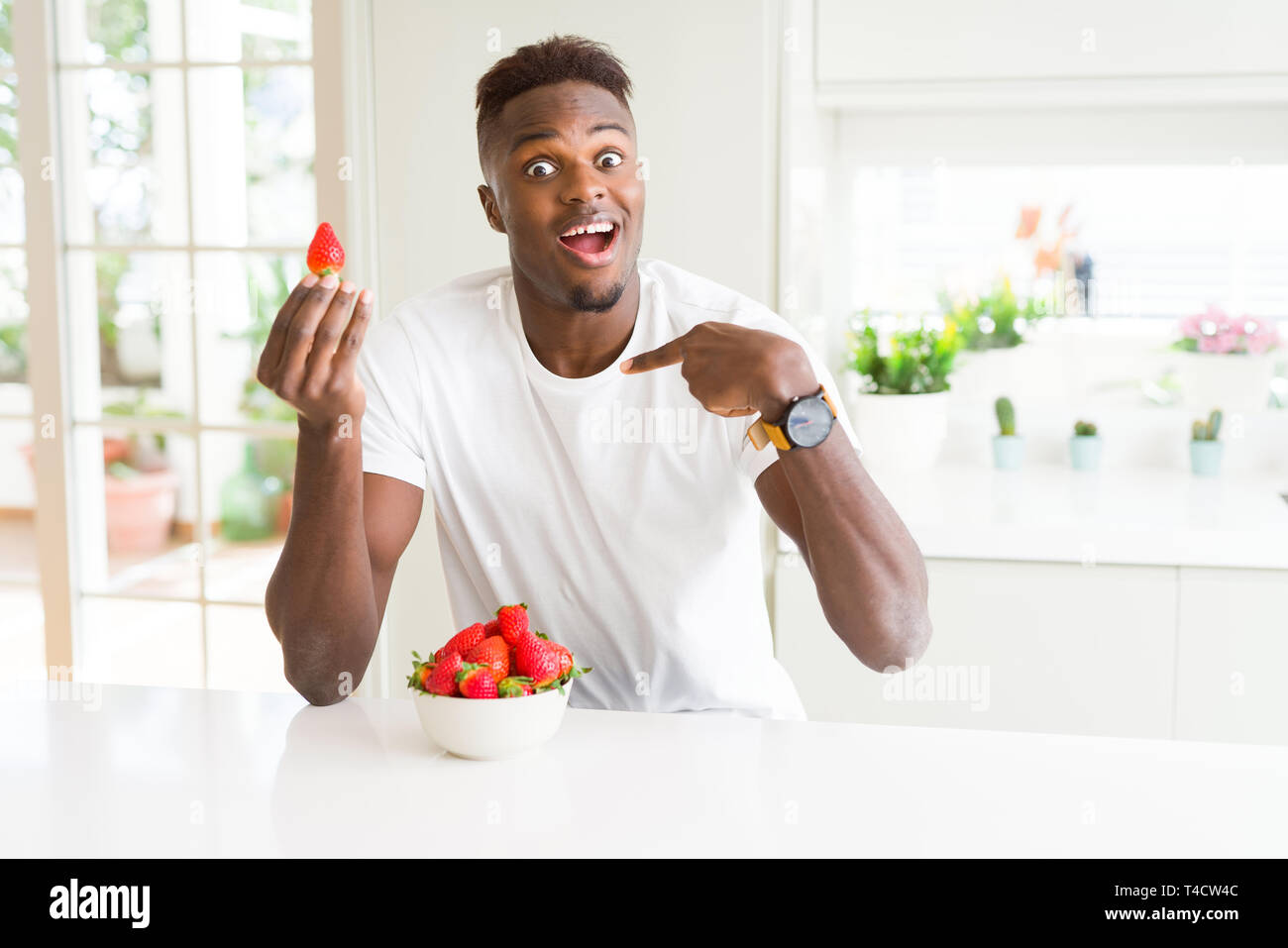 African american man eating fresh healthy strawberries with surprise ...