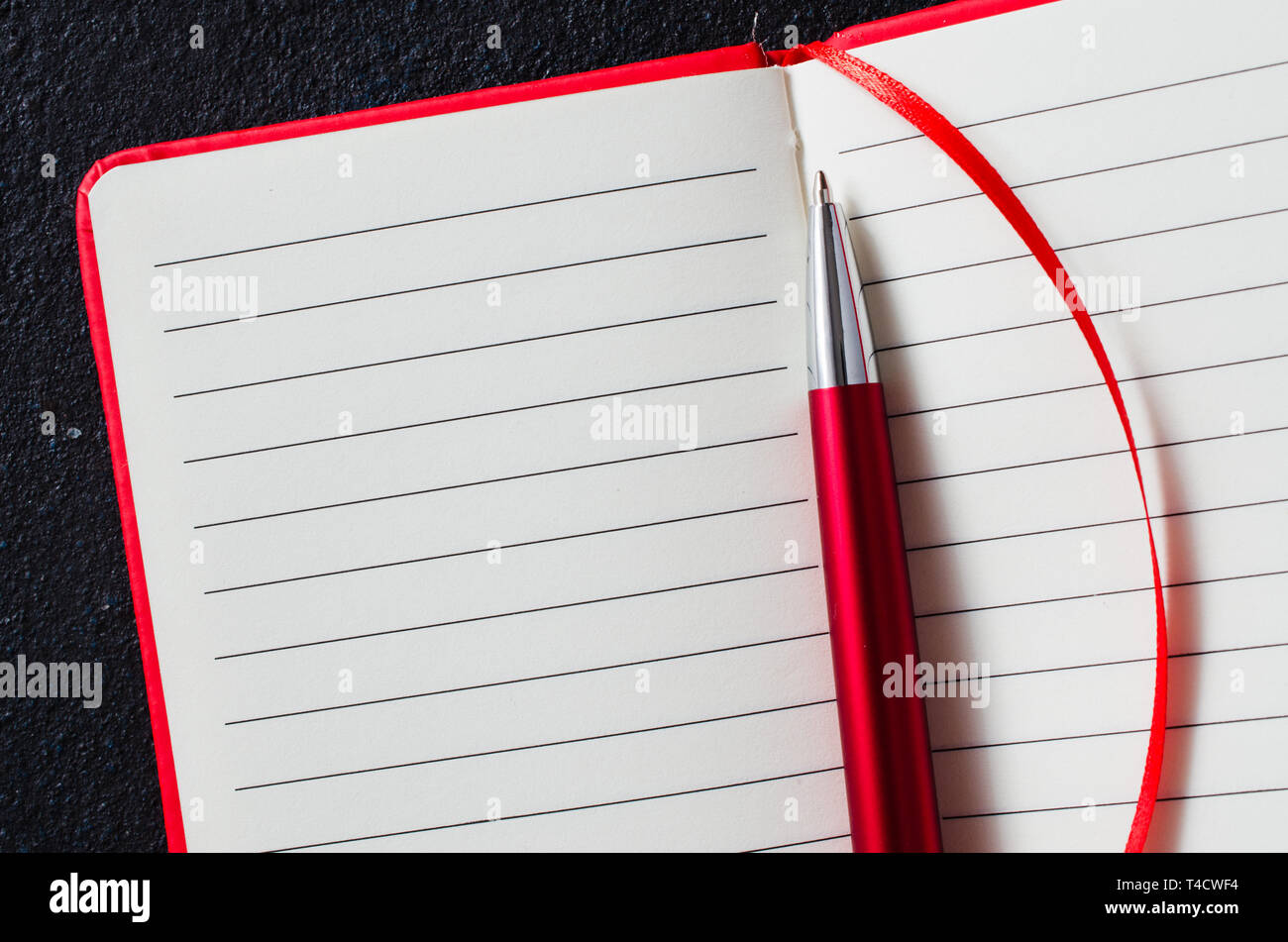 Empty open red notebook with red pen on dark background. Blank paper ...