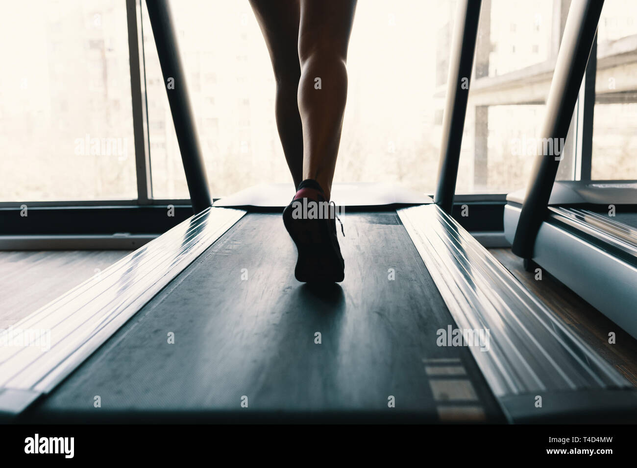 Low-angle view of athletic female legs, jogging on the gym treadmill ...