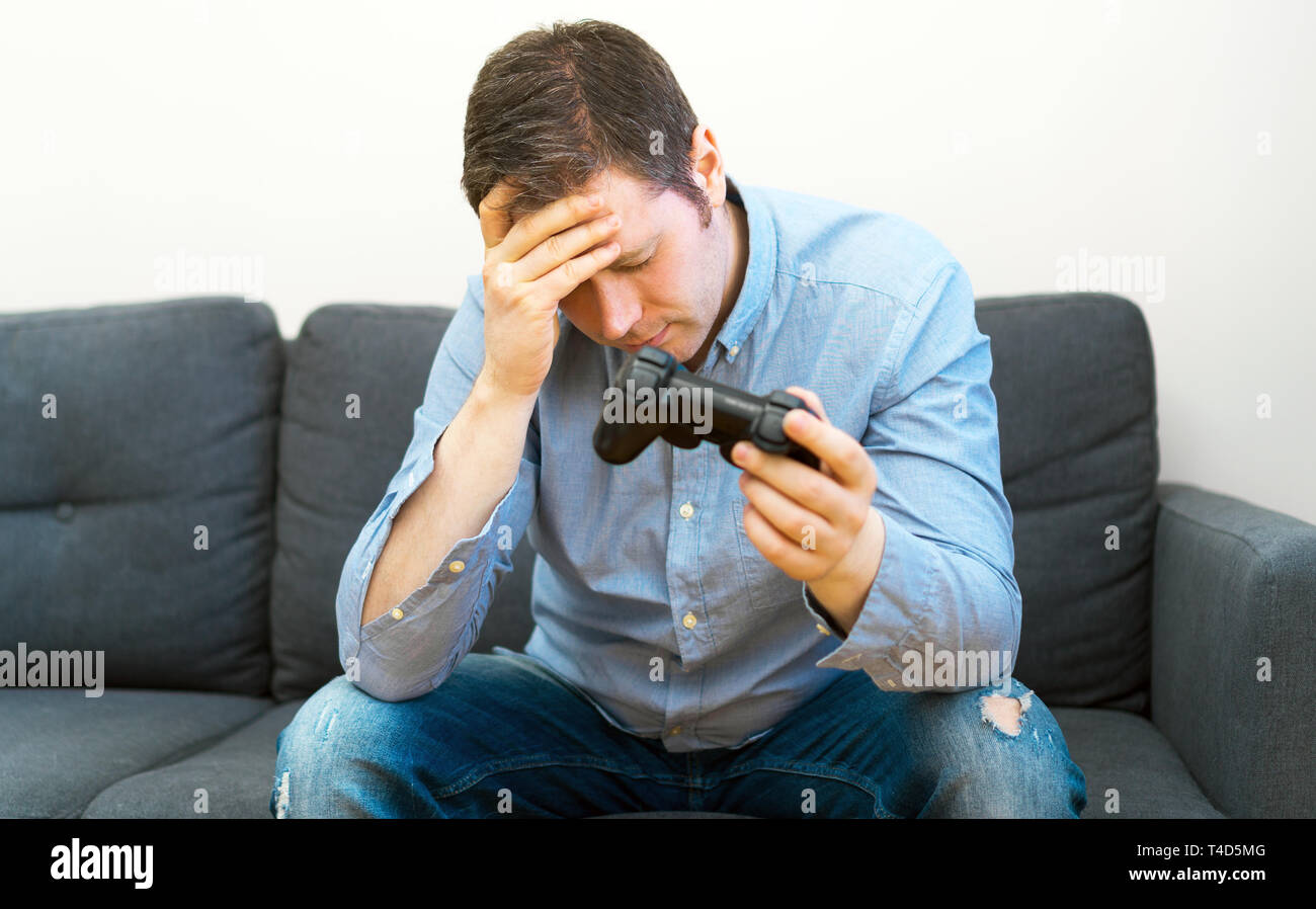 Sad man with gamepad in hands playing video game Stock Photo - Alamy