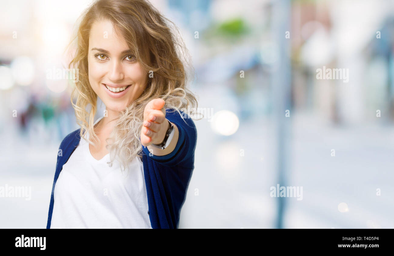Beautiful young blonde woman over isolated background smiling friendly ...