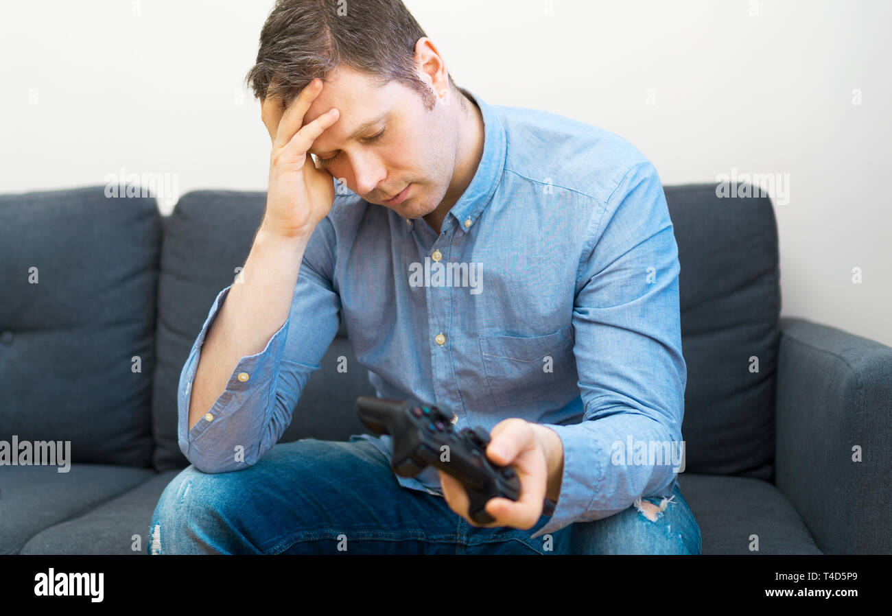 Sad man with gamepad in hands playing video game Stock Photo - Alamy