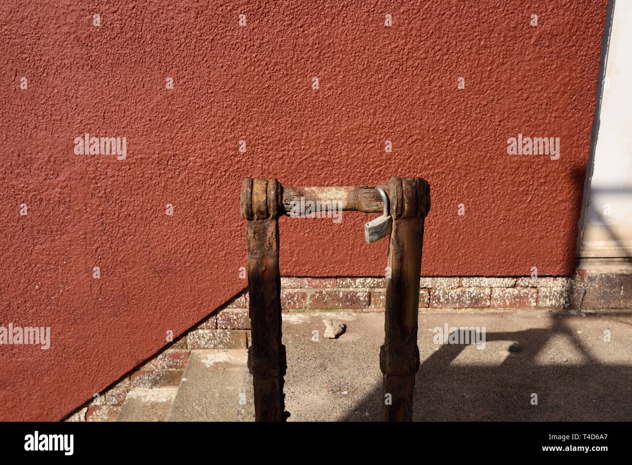Two rusty steel posts and section of handrail with open padlock hanging ...