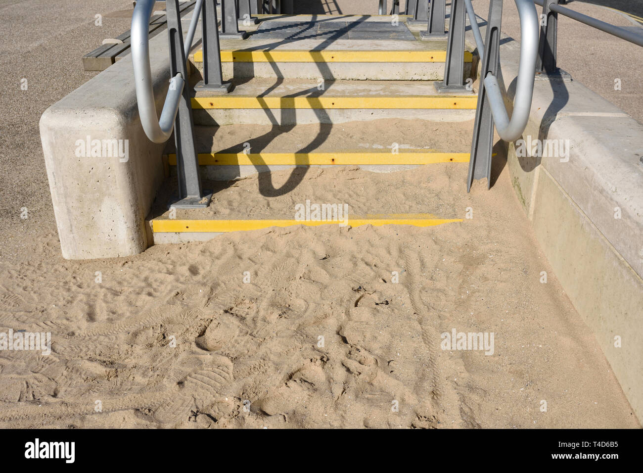Concrete steps with yellow step marker covered with wind blown sand on ...