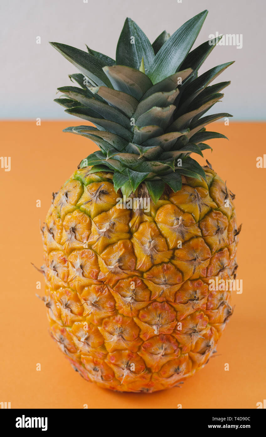 Whole pineapple on orange background Stock Photo - Alamy
